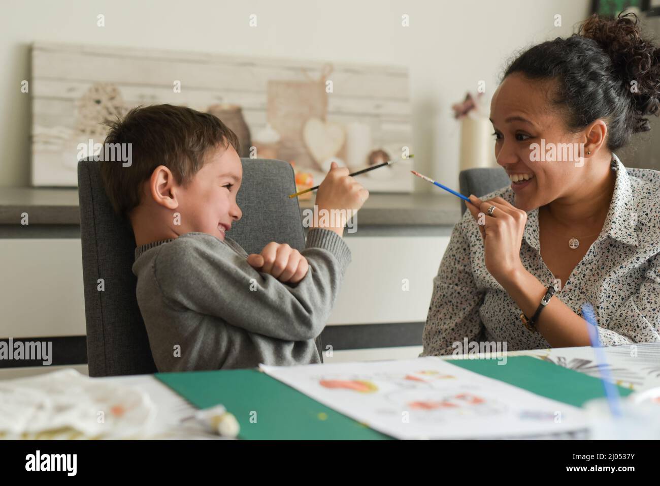 metis mother playing with painting at home with her funny son Stock ...