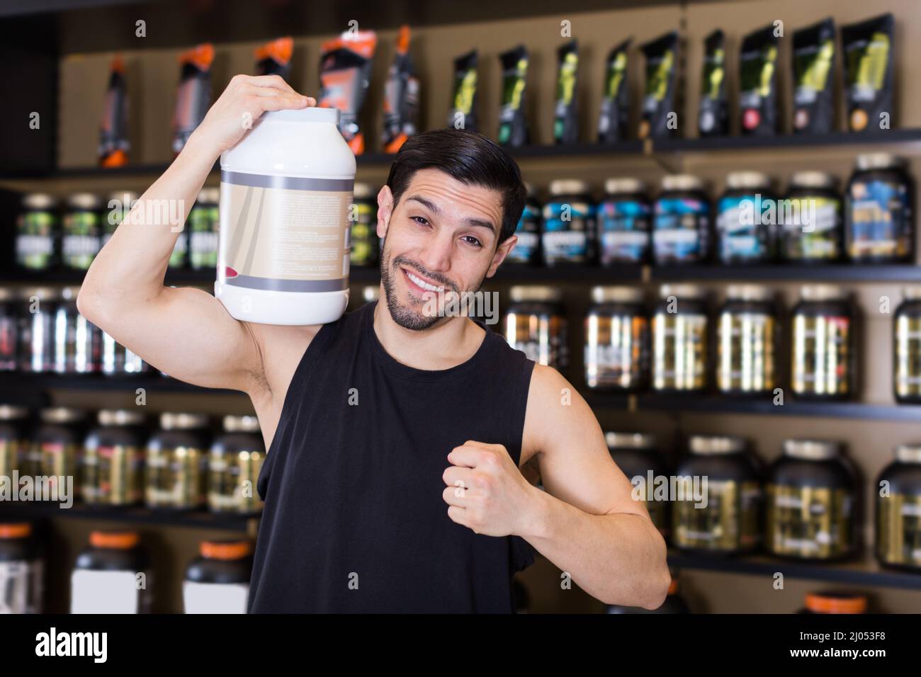 Positive young bodybuilder holding on shoulder sport nutrition products ...