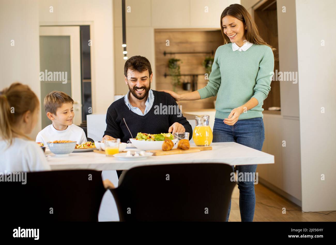 Young mother preparing breakfast for her family in the modern kitchen ...