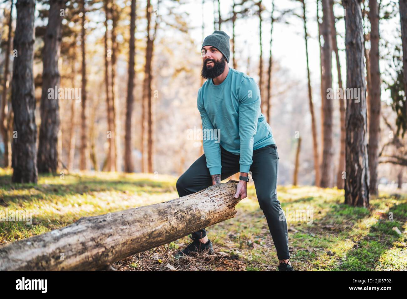 Strong sporty man is lifting tree stump Stock Photo - Alamy