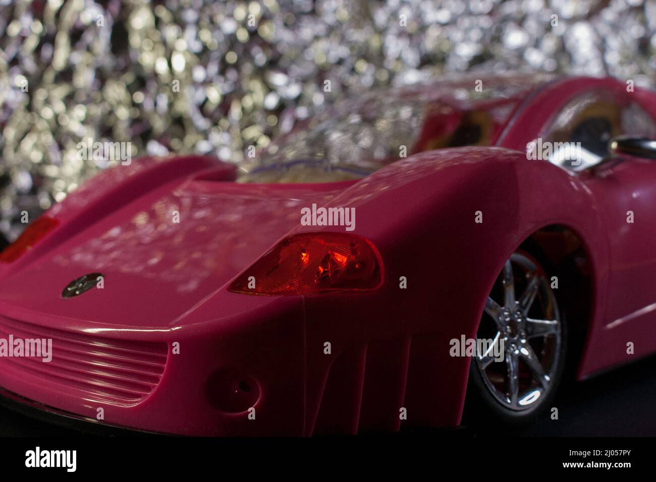 Closeup of a pink barbie car toy with a shiny wall in the background ...