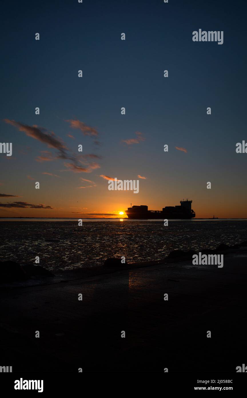 Ship going out into the sea through river mouth. View between two piers ...