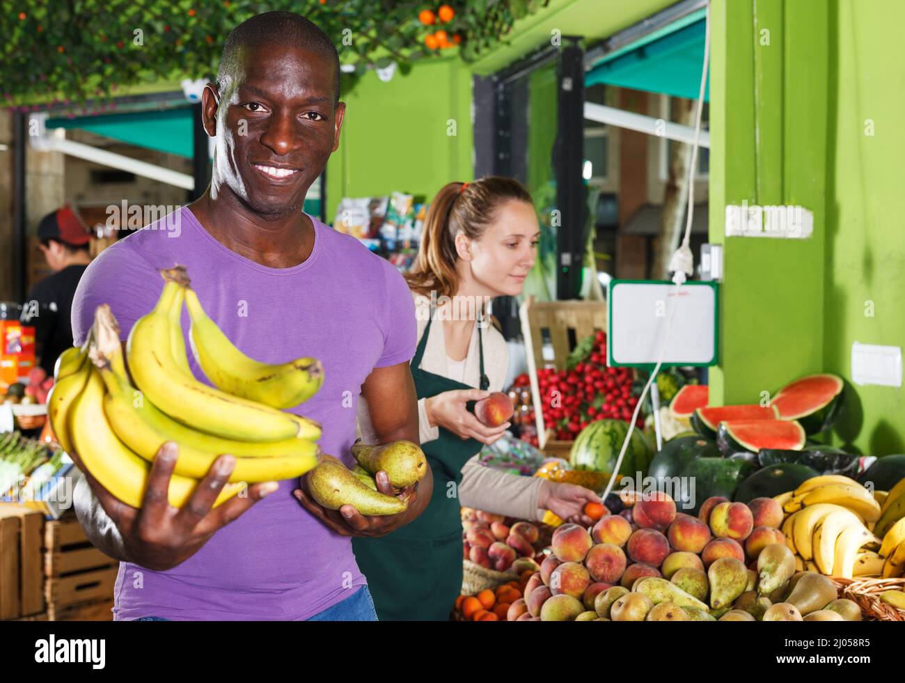 Smiling man is standing with bananas in the fruit market Stock Photo ...