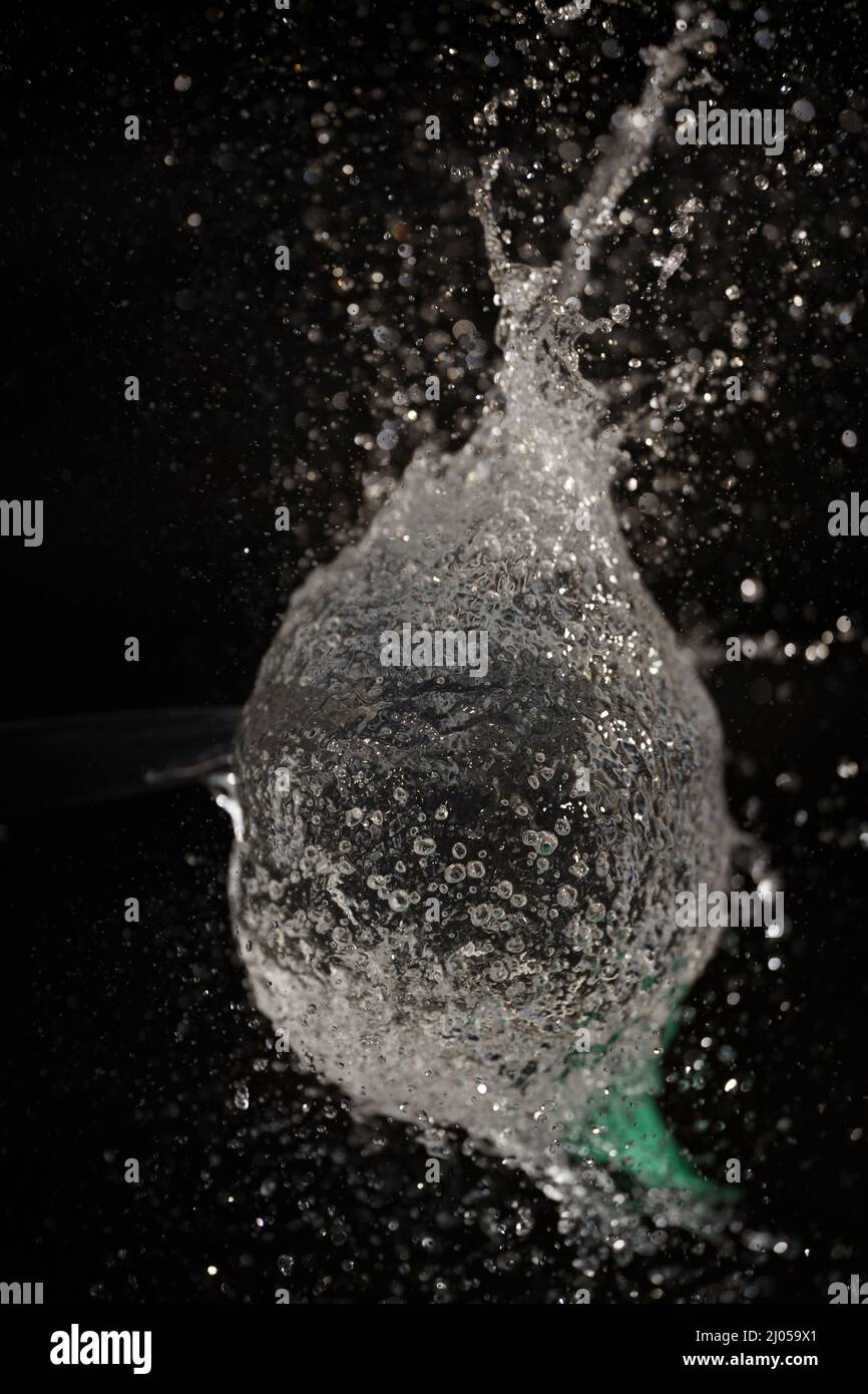 Explosion of water filled balloon on dark background, high speed ...