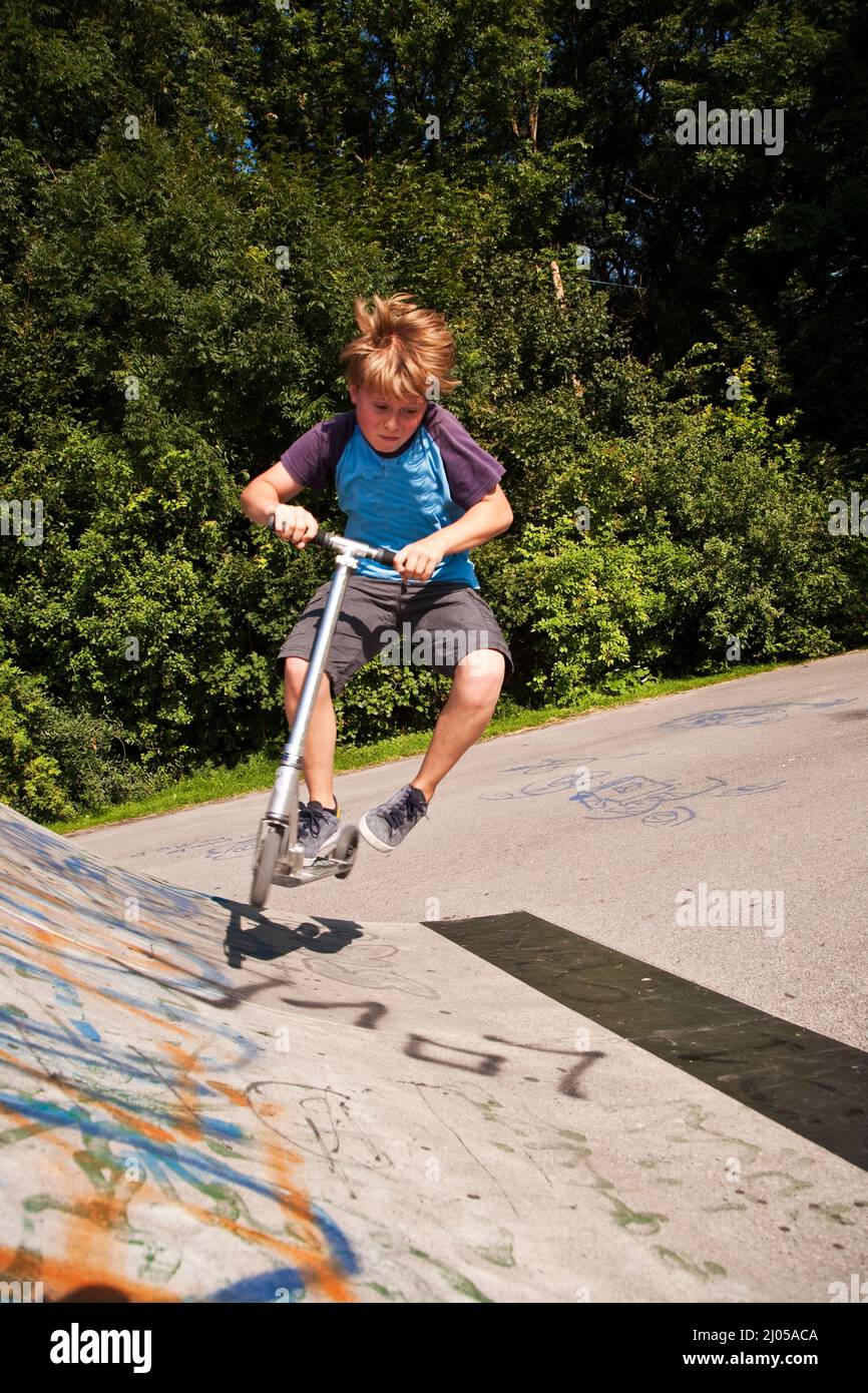 boy has fun scooting in the scating at the skatepark Stock Photo - Alamy