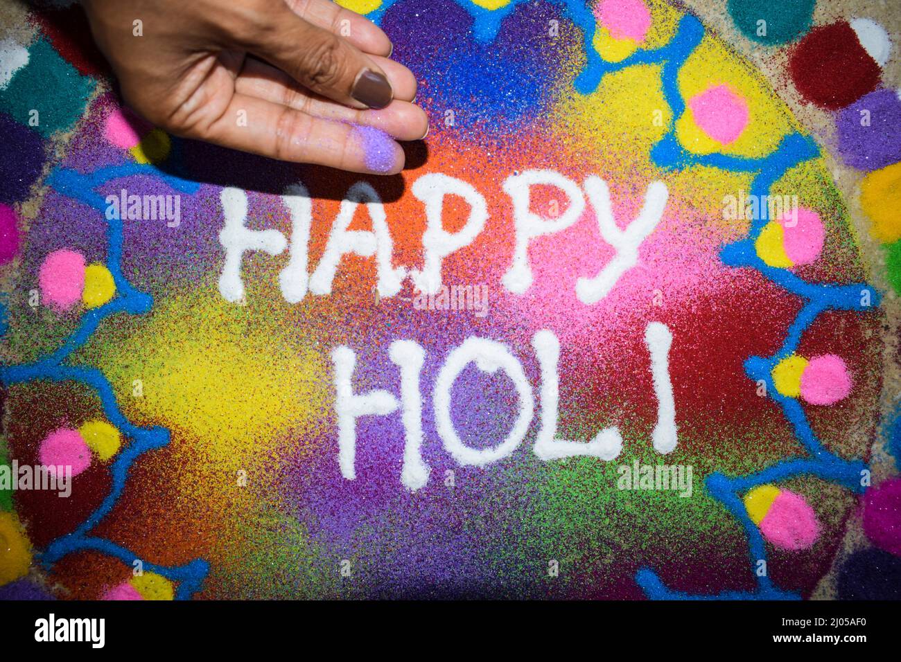 Female making Beautiful and Colourful Happy Holi rangoli made at home ...