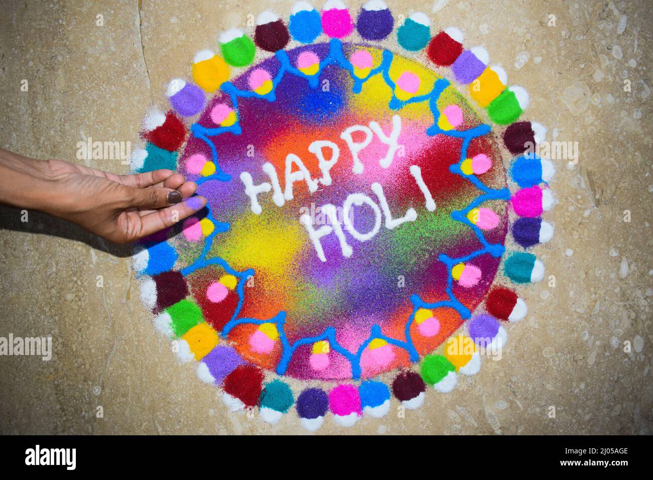 Female making Beautiful and Colourful Happy Holi rangoli made at home ...