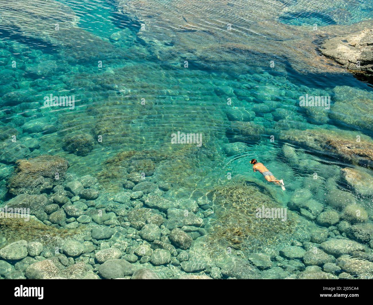 people diving in a natural basin in the rocks coastline of Lanzarote ...