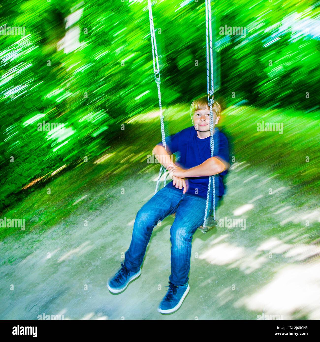 cute boy has fun going on the swings Stock Photo - Alamy