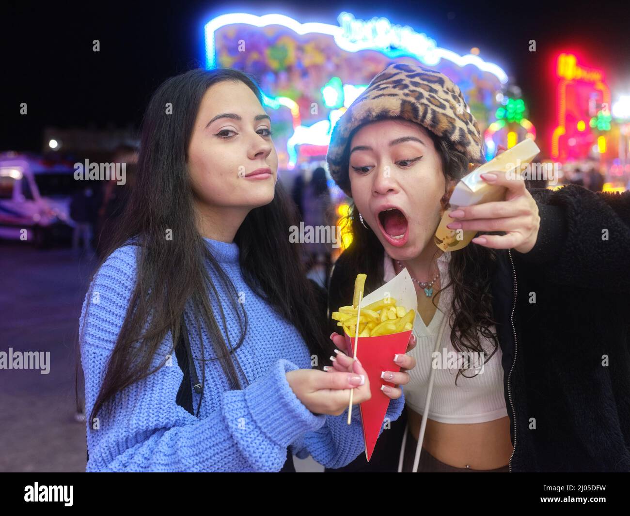 Two friends eating french fries and waffle in a night fair Stock Photo ...