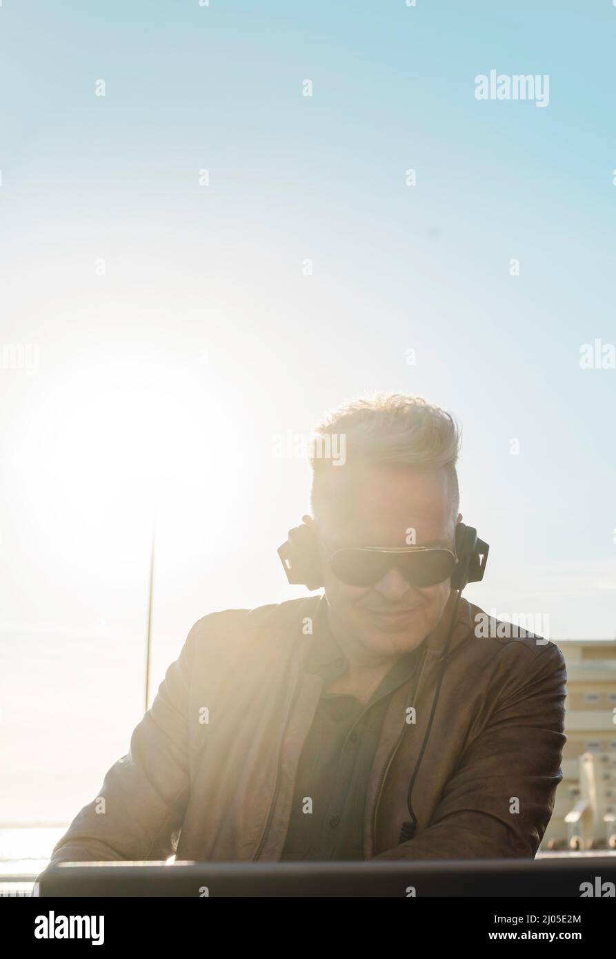 Smiling guy in casual leather jacket looking down in a music disco club ...