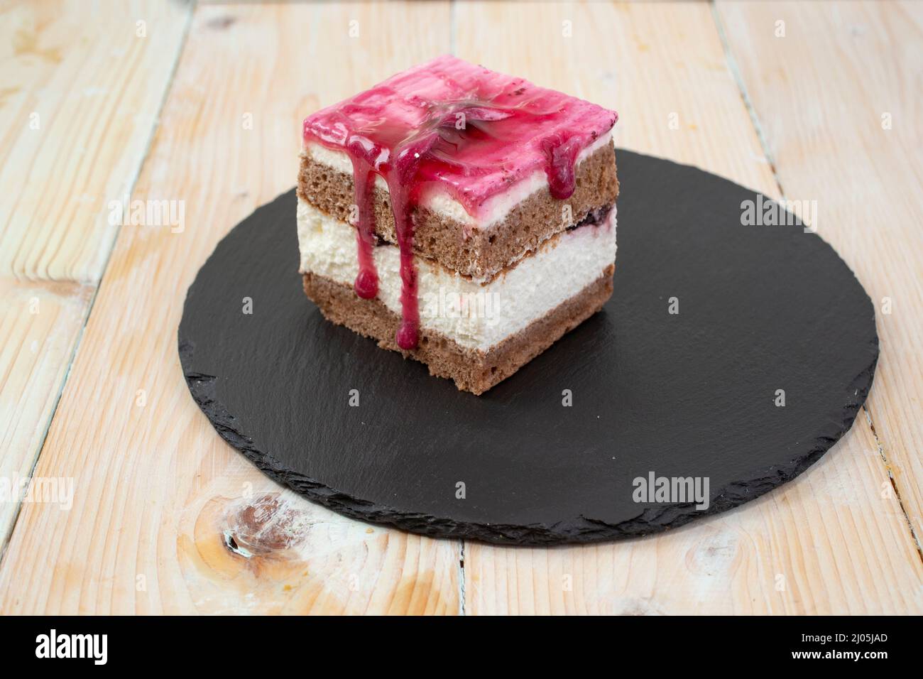 cube cut forest fruit cake, on a black stone tile. Side view Stock ...