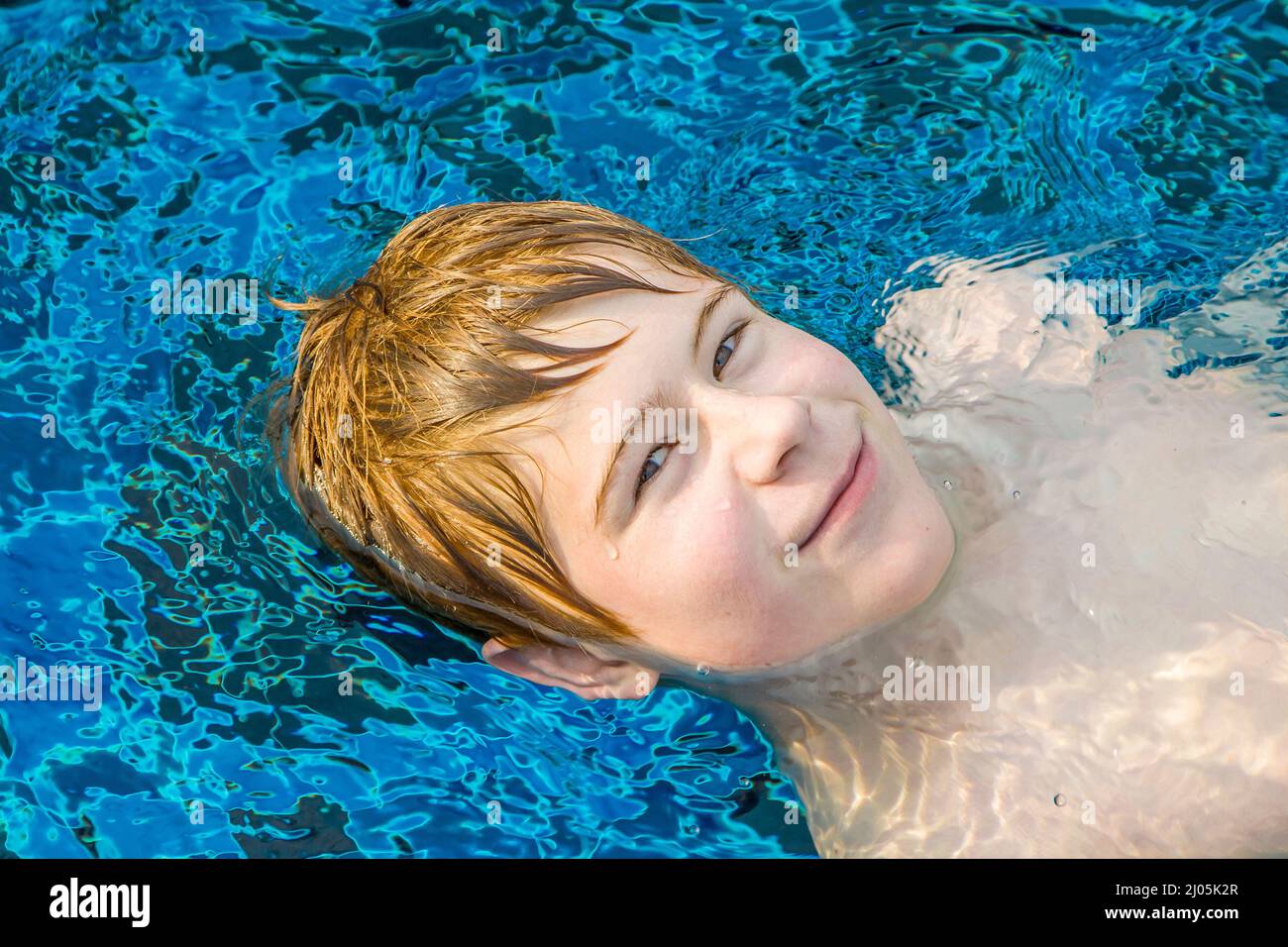 boy enjoys floating on his back in the pool Stock Photo - Alamy