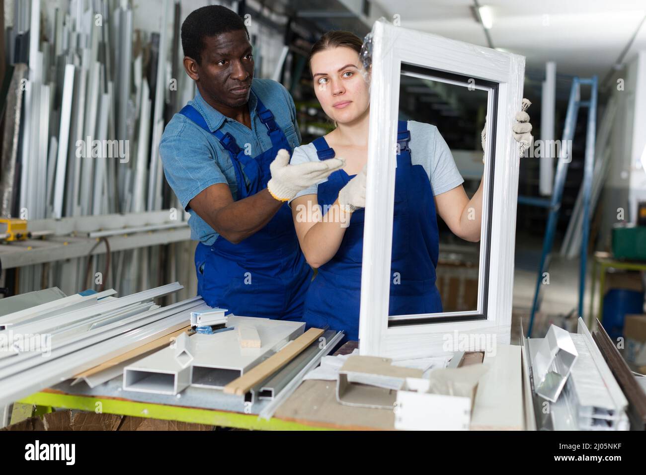 Portrait of man and woman worker who are standing with window frames in ...