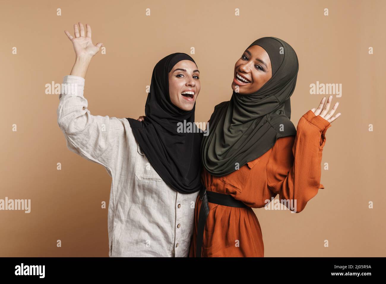 Young muslim women in hijab hugging and laughing at camera isolated ...