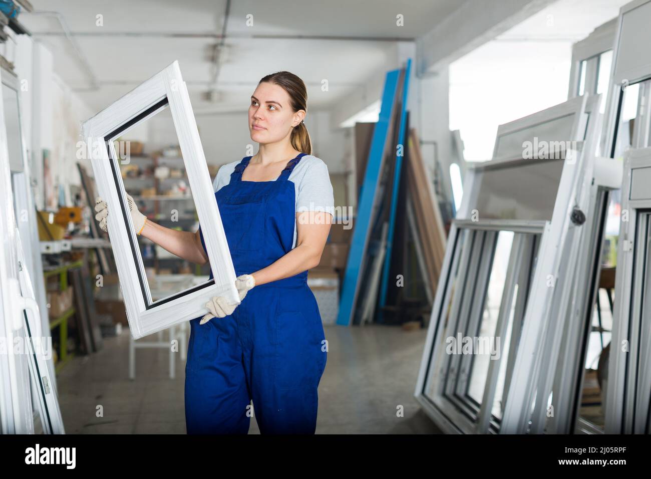 Young woman master is looking on modern window frame in the workshop ...