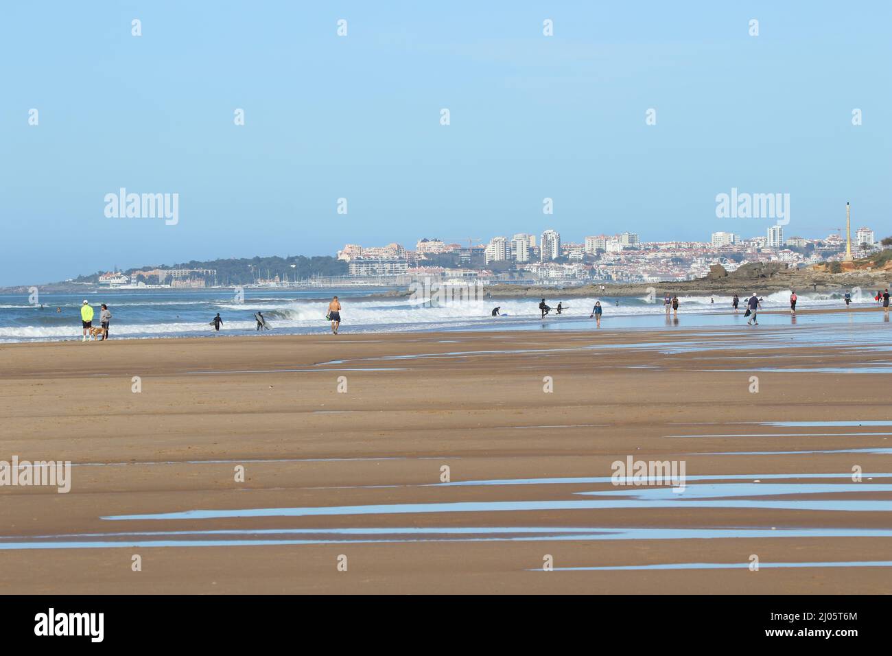 People walking on a wet beach in the background of a cityscape Stock ...