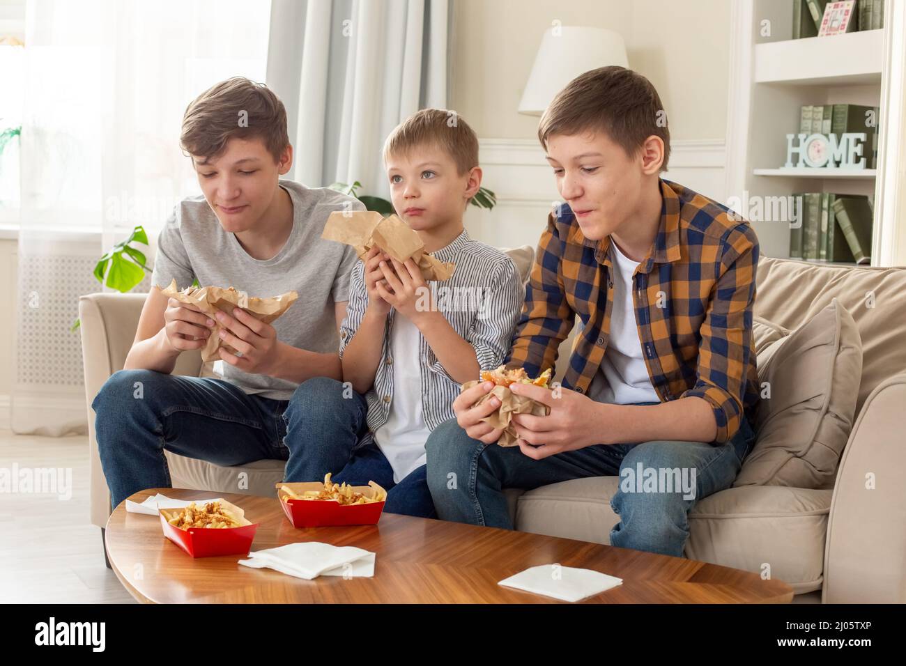 A happy three teenage boys, eating fast food in living room Stock Photo ...