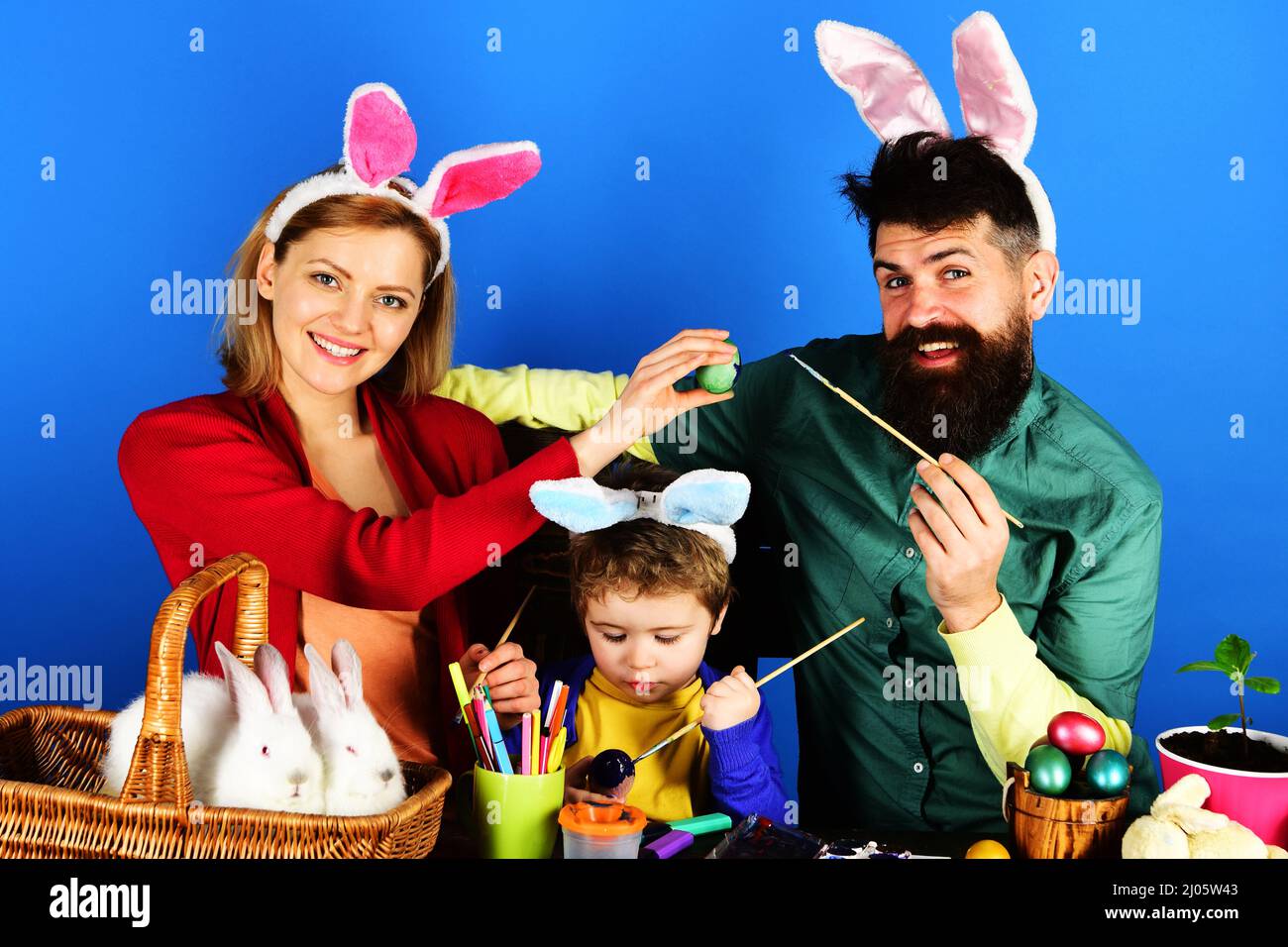 Easter day. Happy family in bunny ears painting eggs for holiday ...