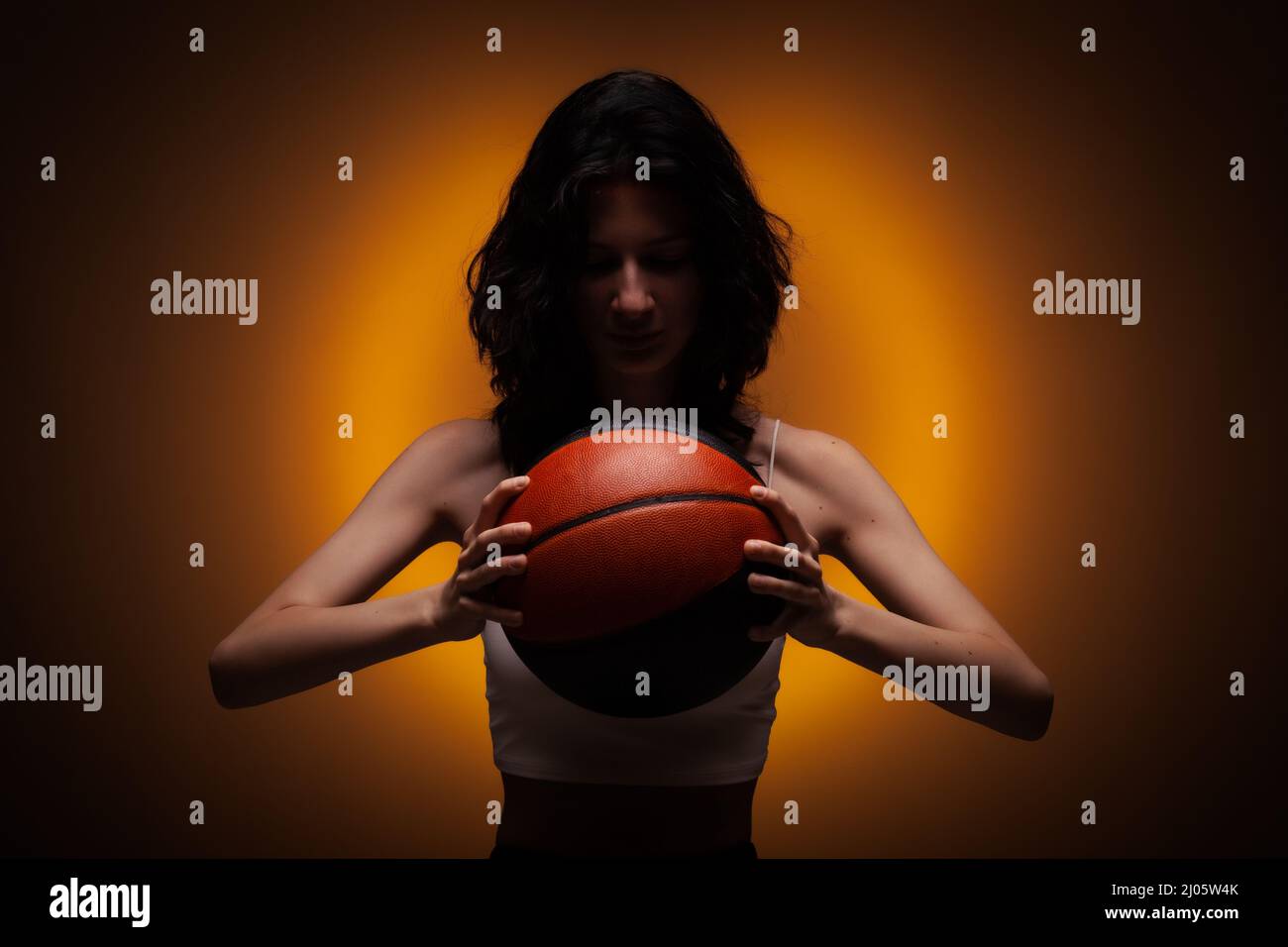 Teenage girl with basketball. Studio portrait on orange colored ...