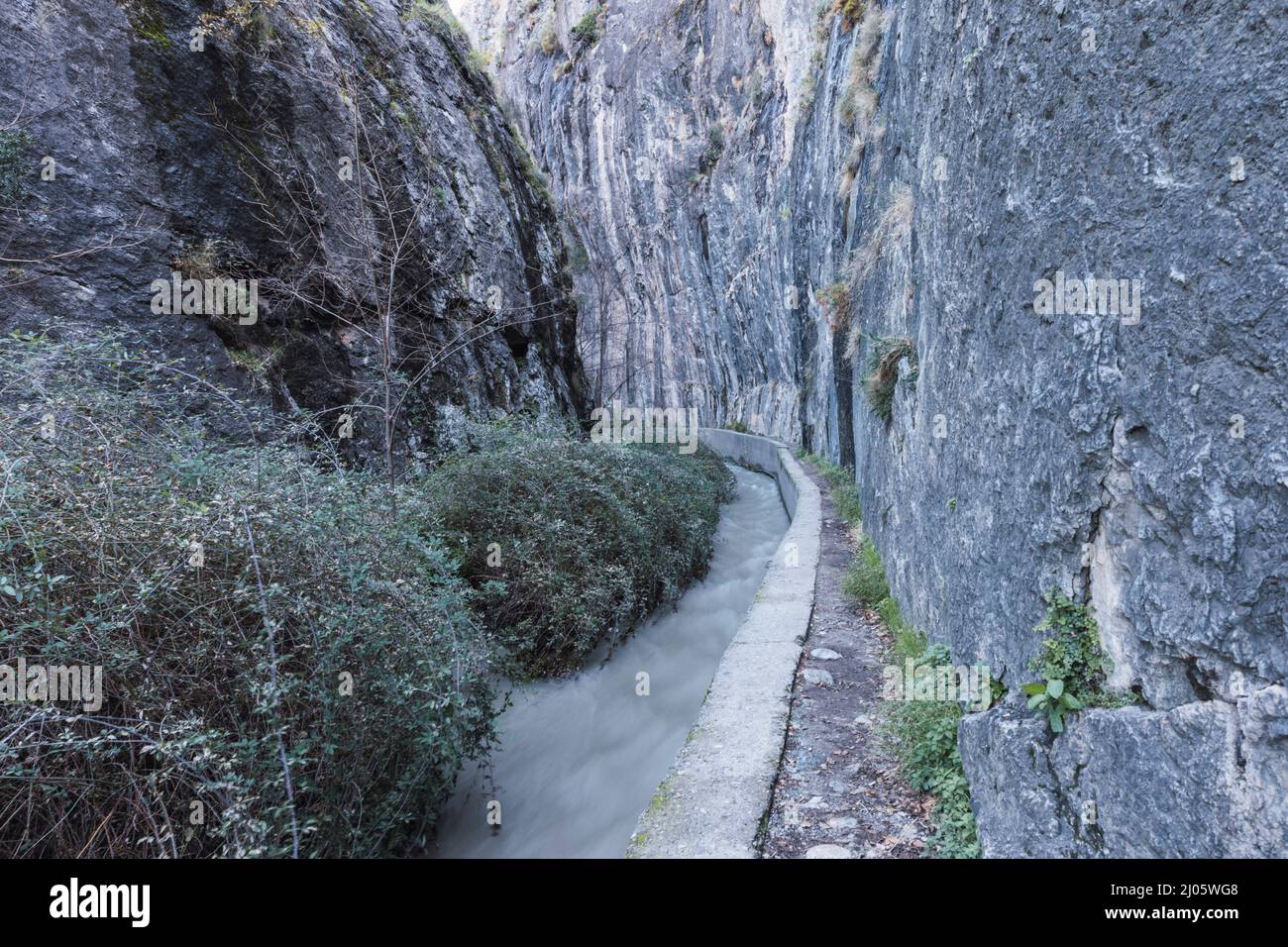 Ditch full of water between mountain walls on the route of the river ...