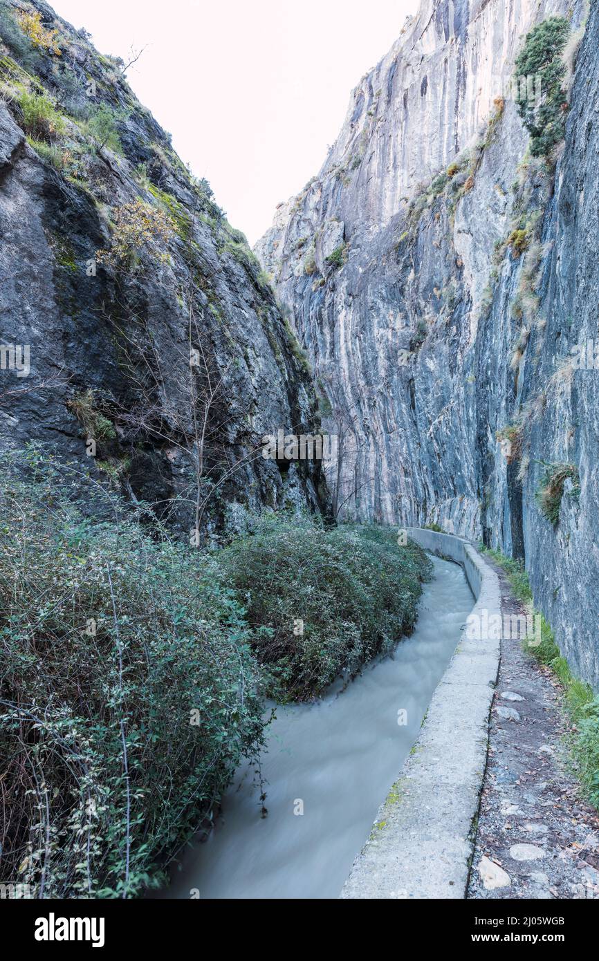 Vertical photo of a water-filled irrigation ditch between mountain ...
