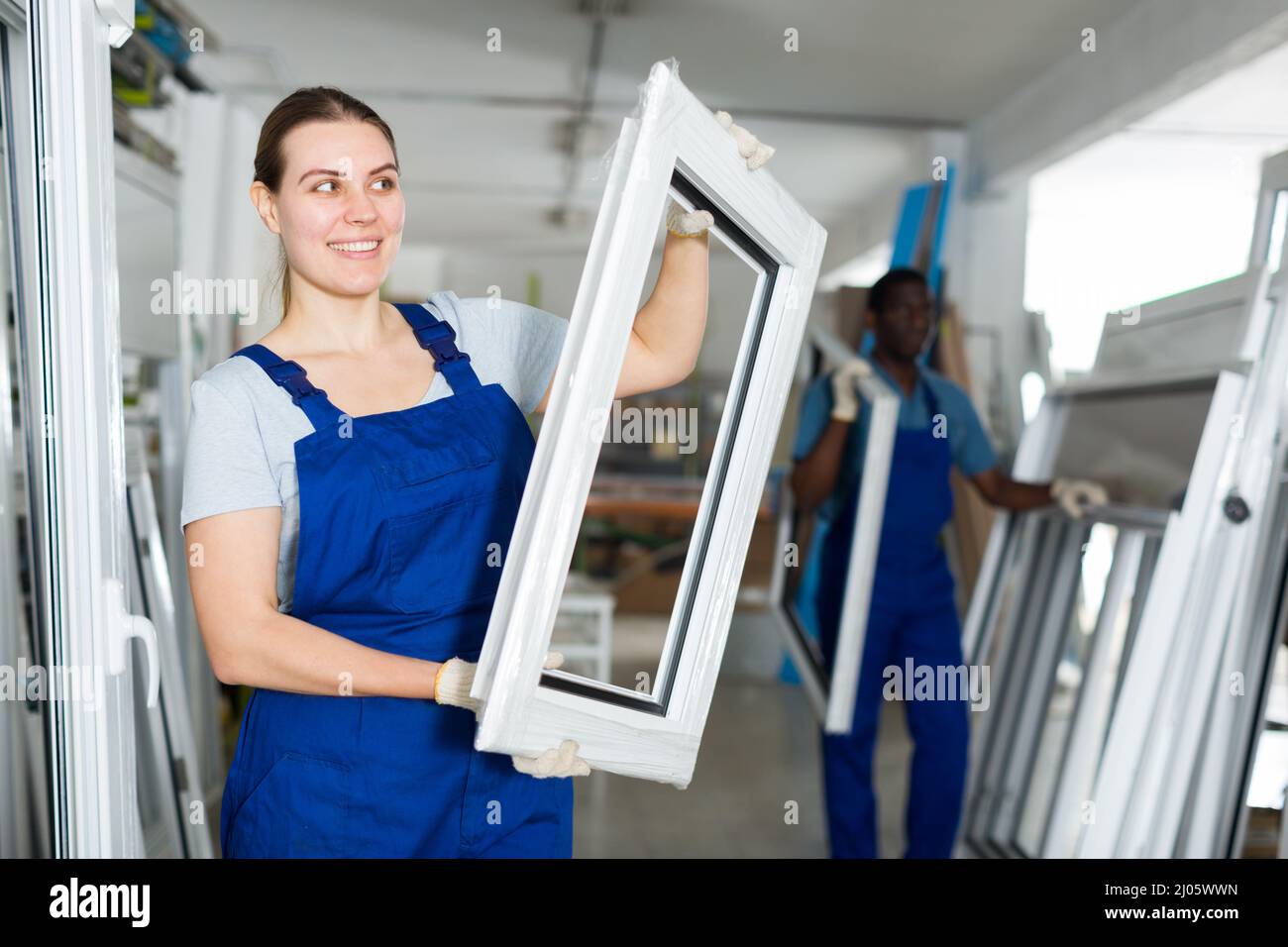Young woman master is looking on modern window frame in the workshop ...