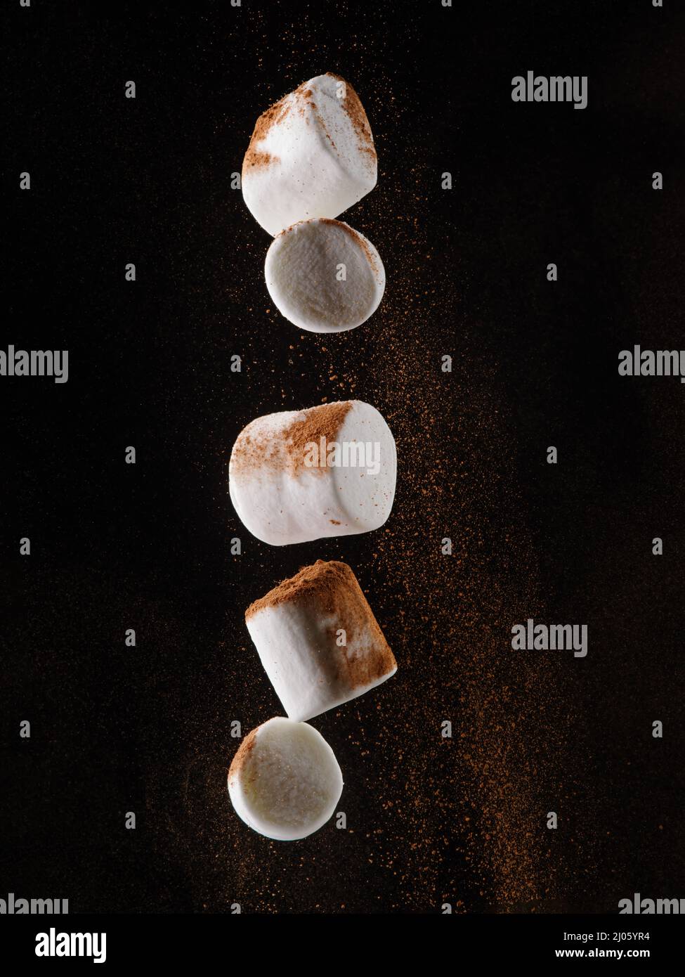 White marshmallow pieces in chocolate chips in frozen flight on a black ...
