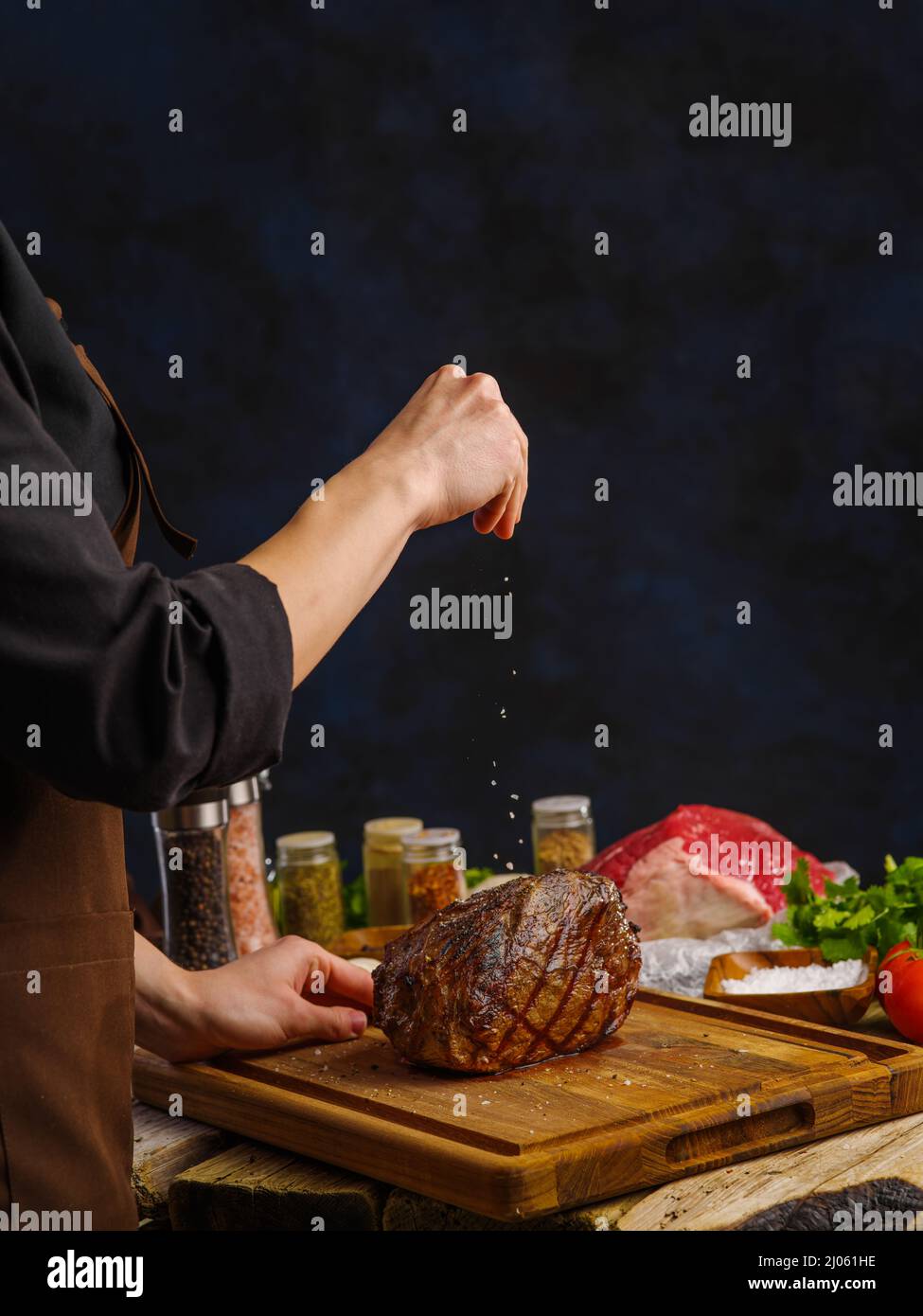 The chef sprinkles spices on a baked ham on a cutting board. Healthy ...