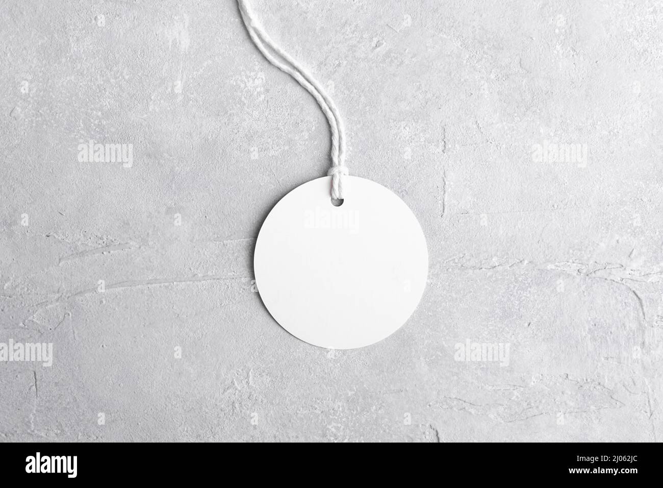 Round white tag mockup with white cord, close up. Blank paper price tag ...
