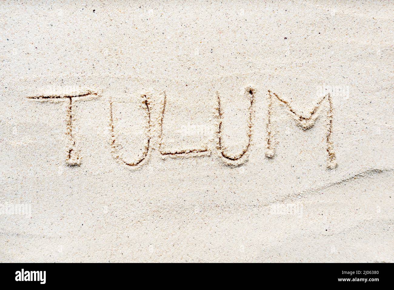 Handwriting words "Tulum" on sand of beach Stock Photo - Alamy