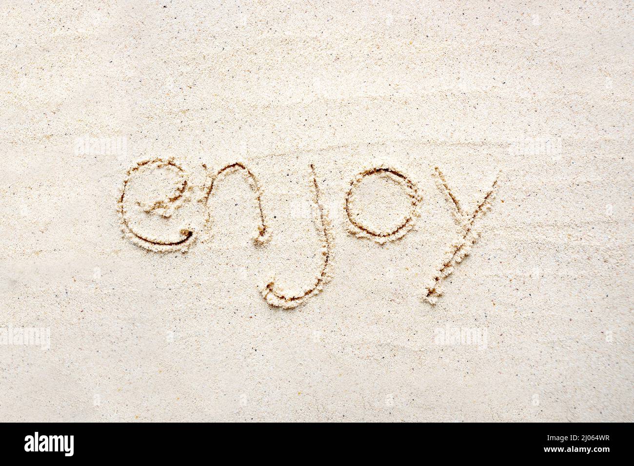 Handwriting words "Enjoy" on sand of beach Stock Photo - Alamy