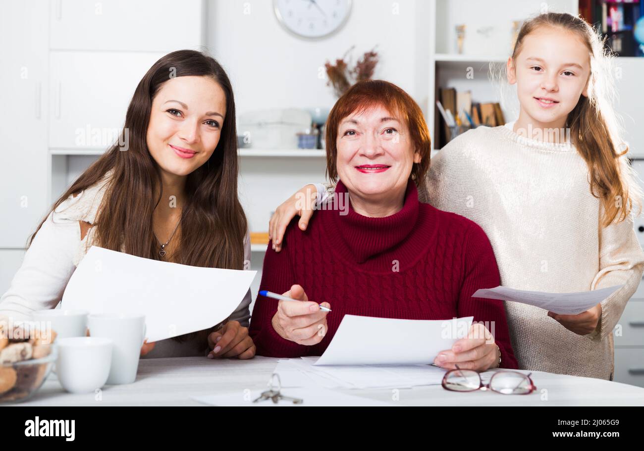 Three generations of happy family working together with documents at ...