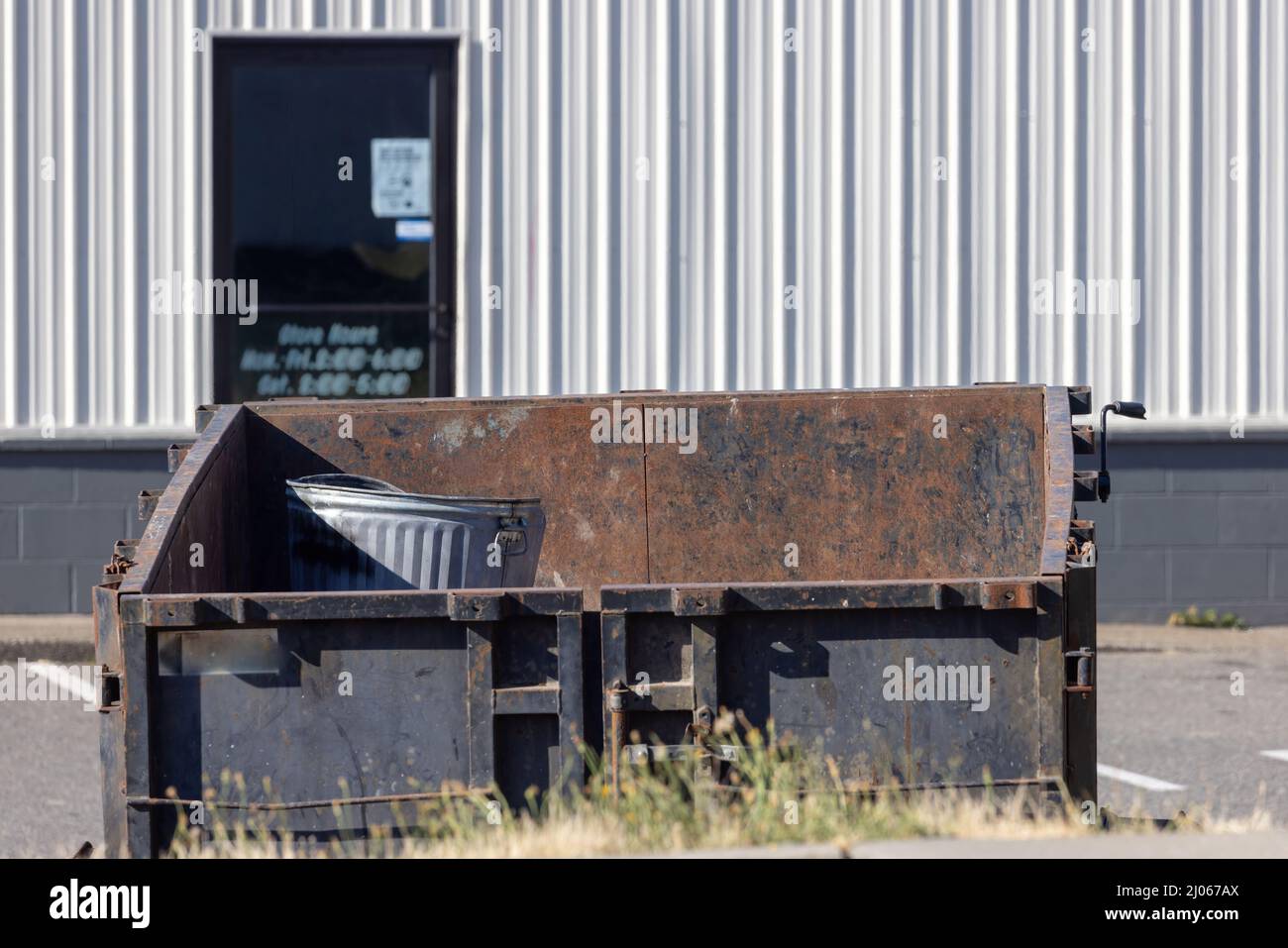 big rusted garbage dumpster sitting in parking lot Stock Photo - Alamy