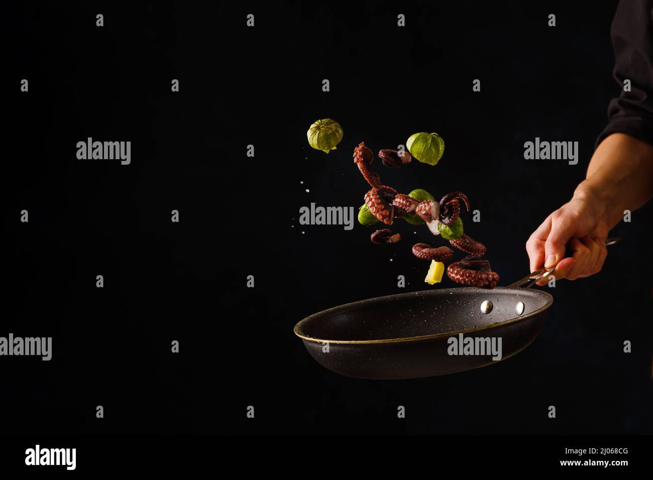 A professional chef prepares seafood - octopus with vegetables in a ...