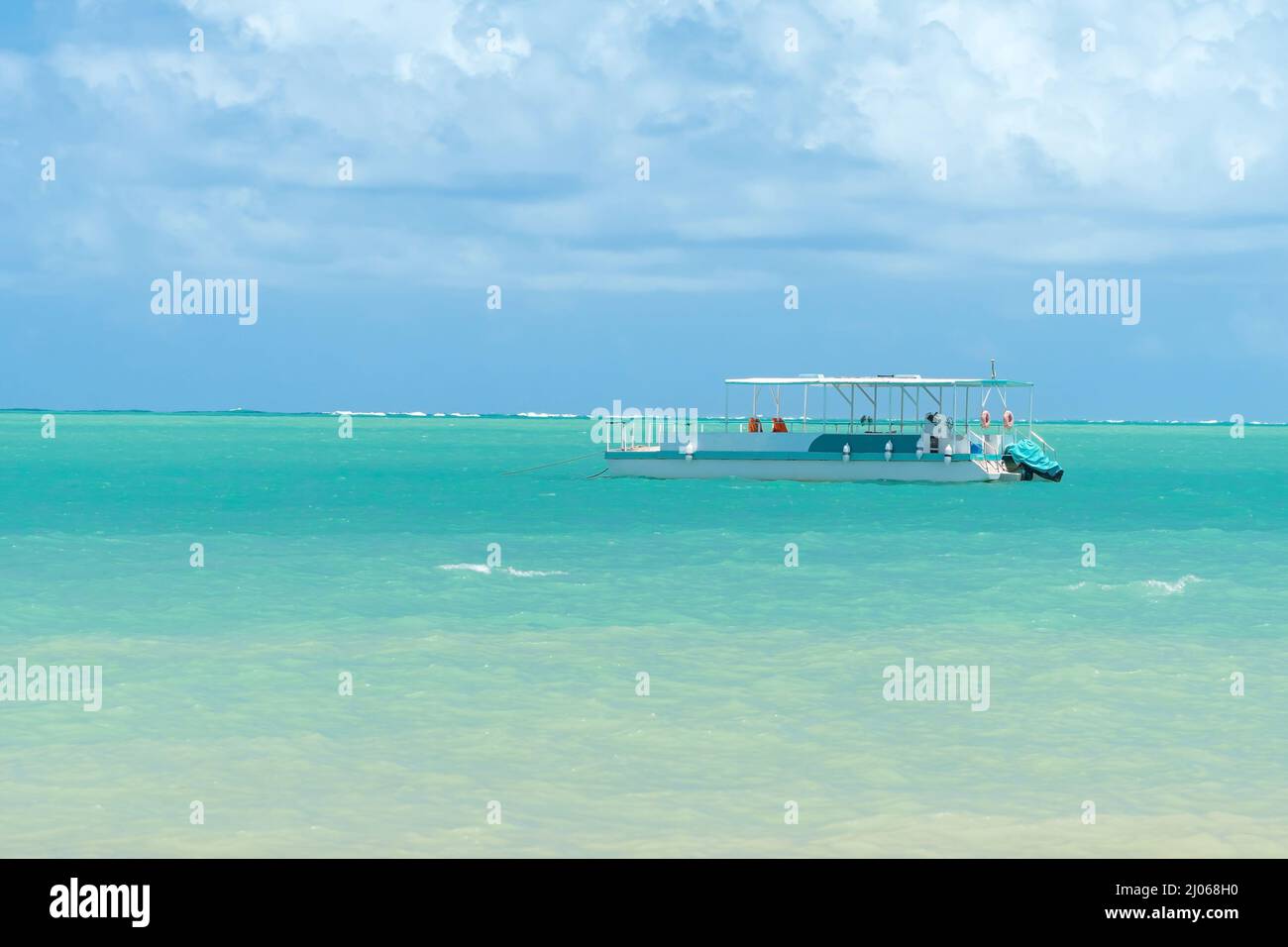 Tourist catamaran moored on a beautiful beach with cyan-toned waters ...