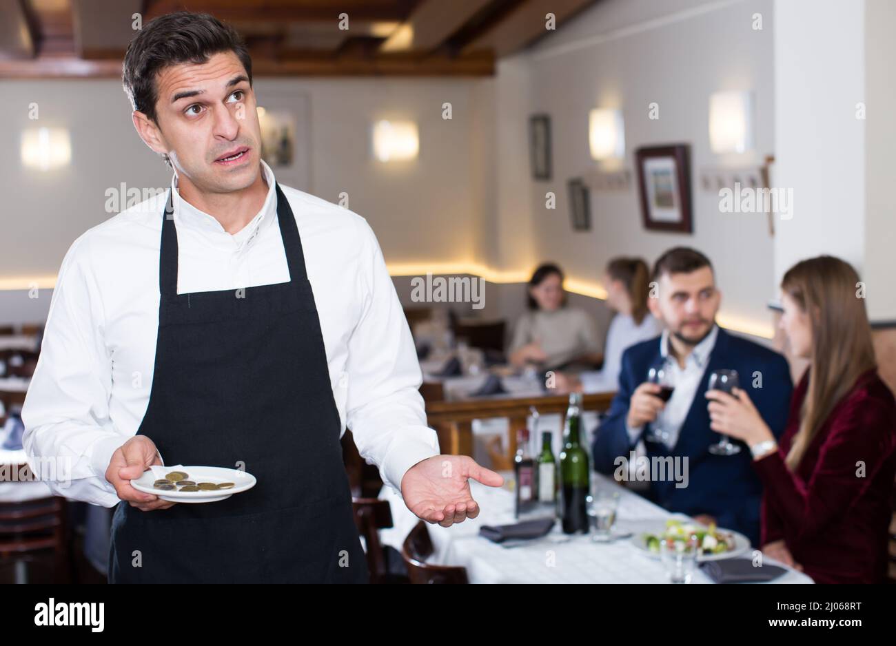 Portrait of waiter dissatisfied with small tip from restaurant visitors ...