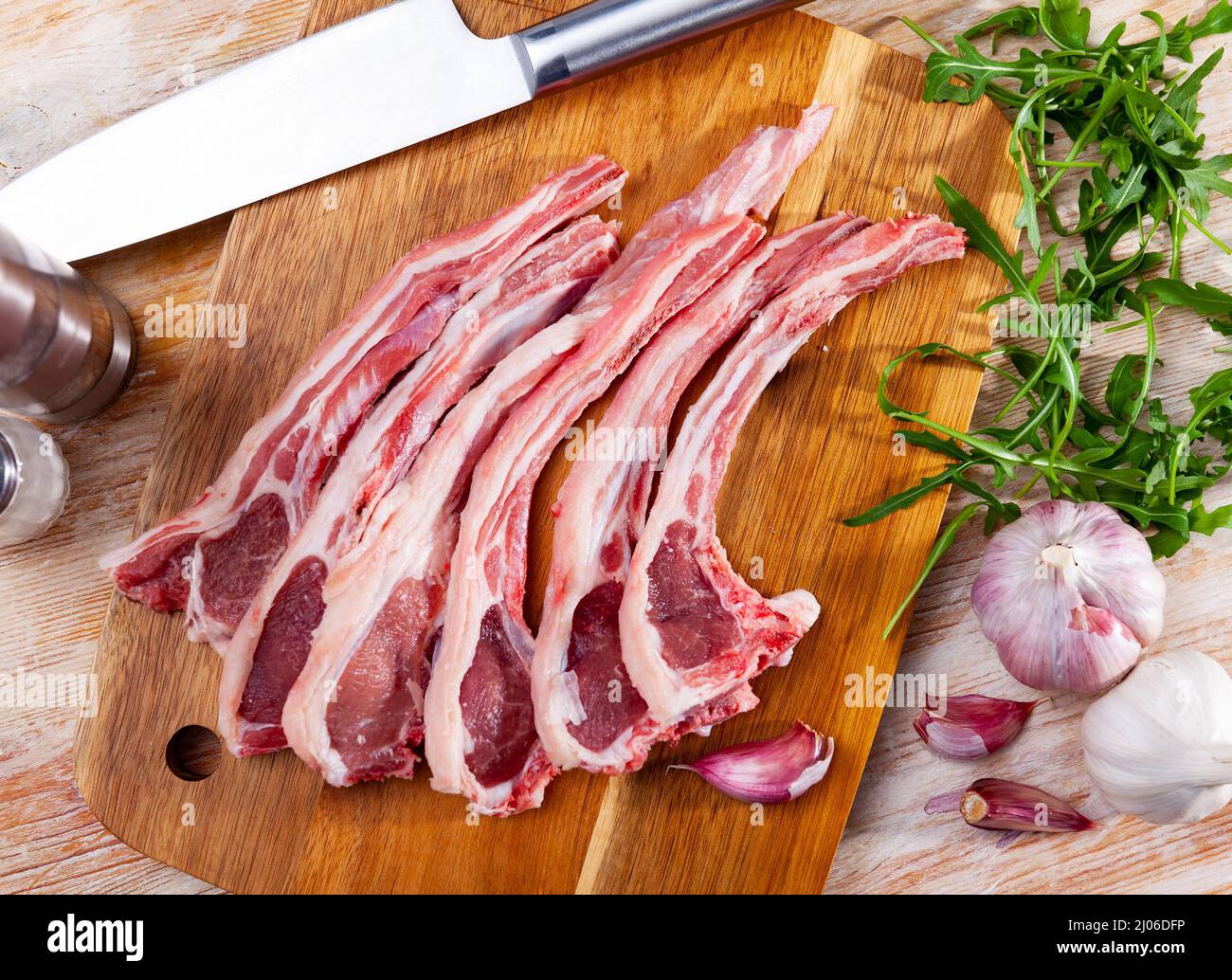 Raw lamb chops on wooden cutting board with garlic and herbs Stock ...