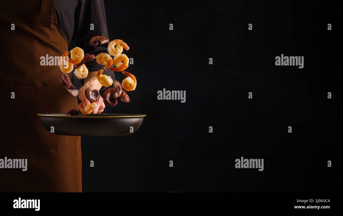 A professional chef prepares seafood - shrimp and octopus on a frying ...