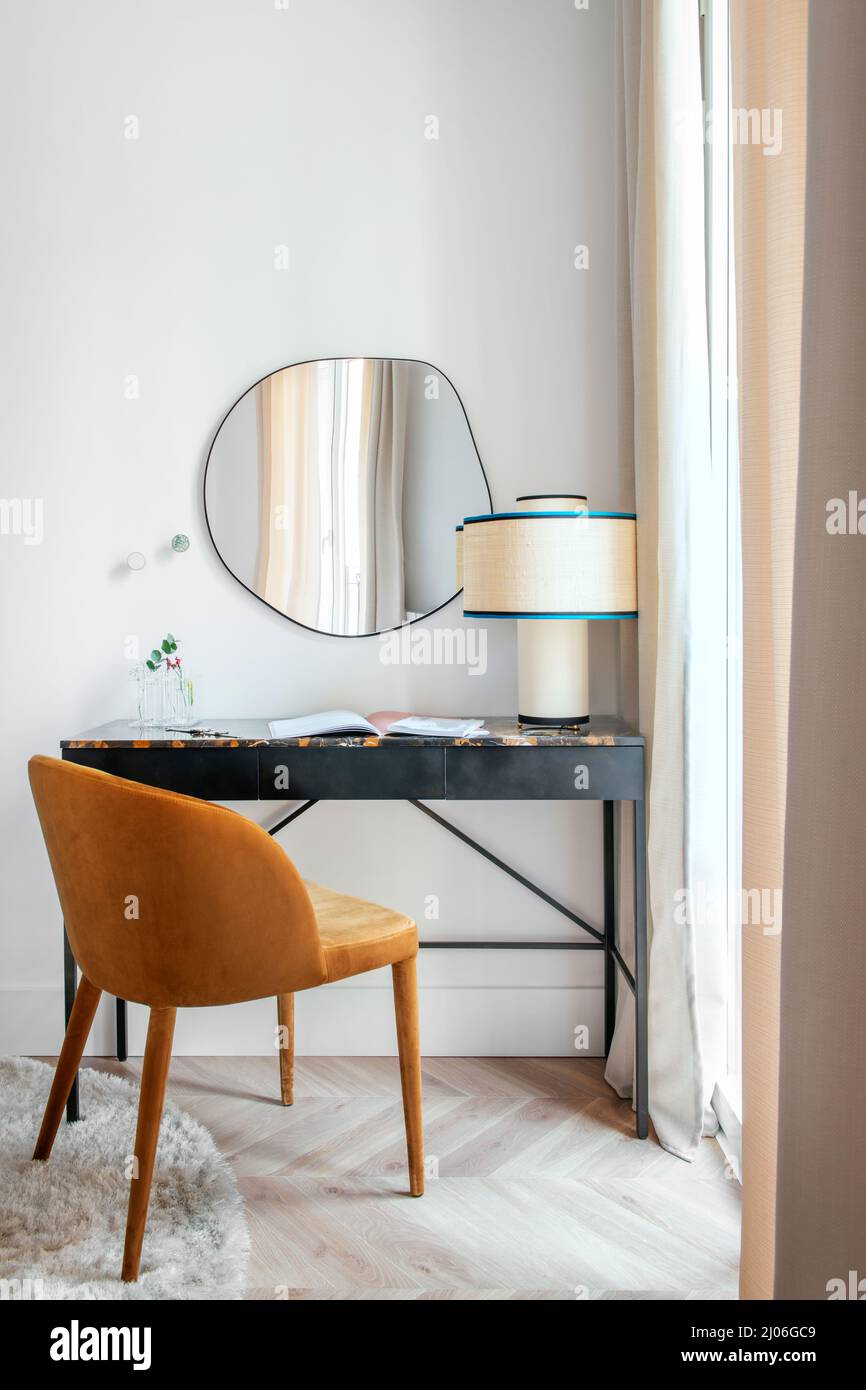 Desk with black table, decorative lamp, misshapen mirror and orange ...