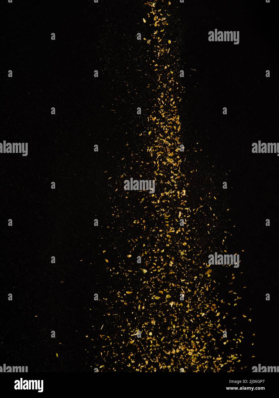 Golden flow of exotic spices in frozen flight on black background ...