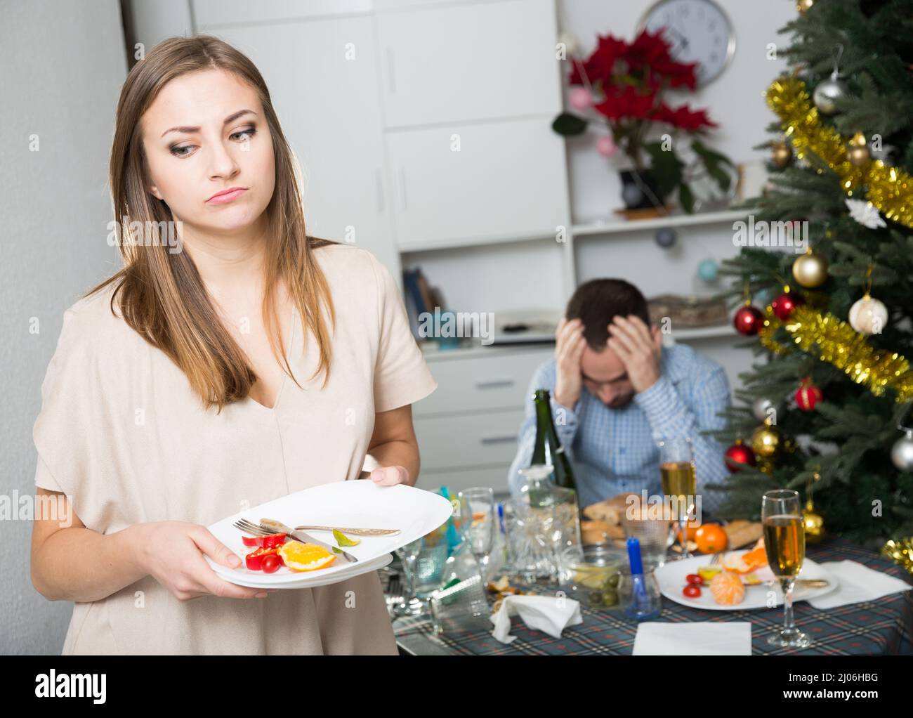 Upset young woman clearing table after Christmas celebration on ...