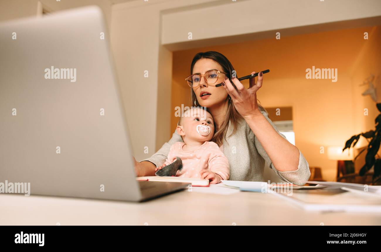 New mom speaking on a phone call in her home office. Multitasking mom ...