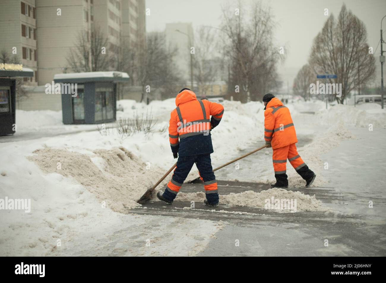 Workers are clearing snow. Men shovel clear road of snow. Communal ...