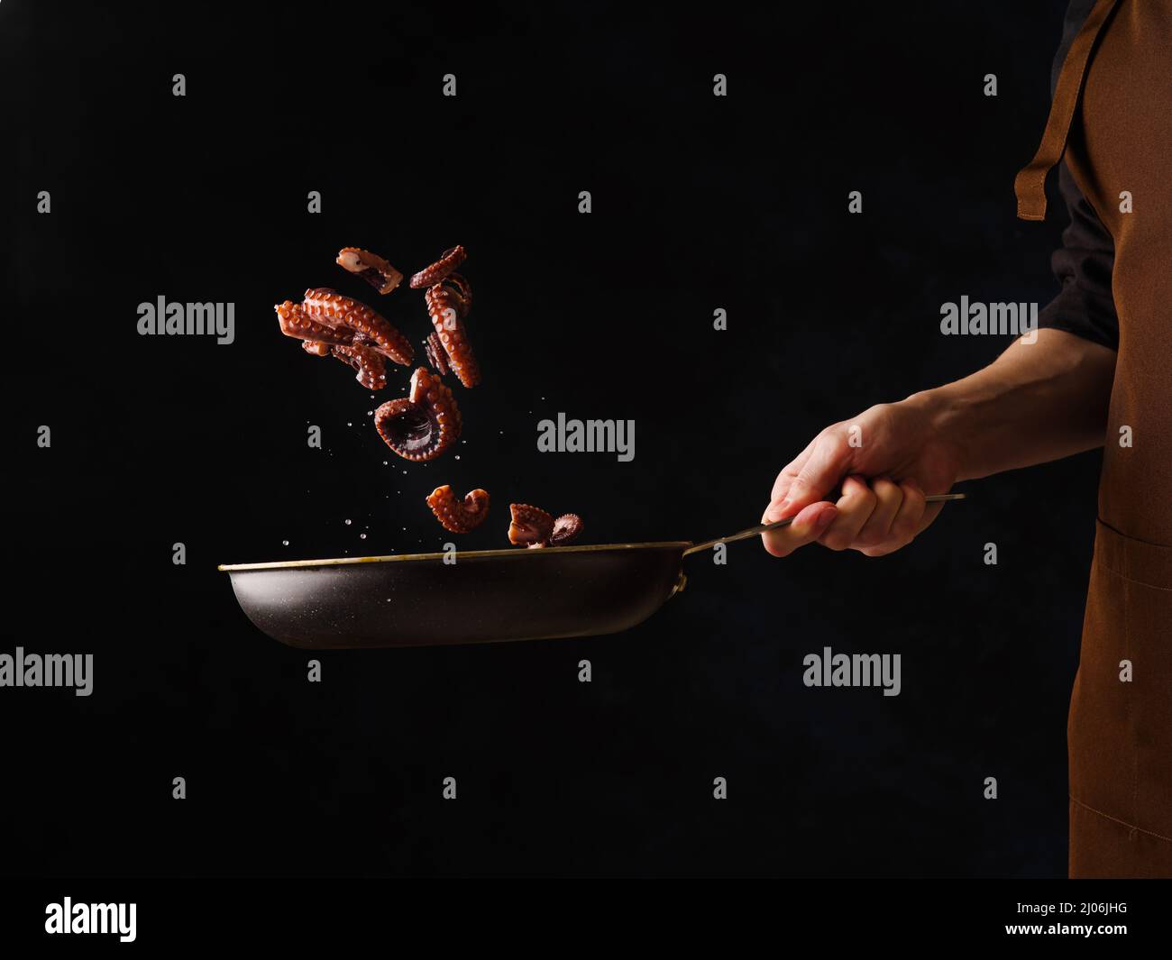 Sea food. Octopuses in a pan in a frozen flight on a black background ...