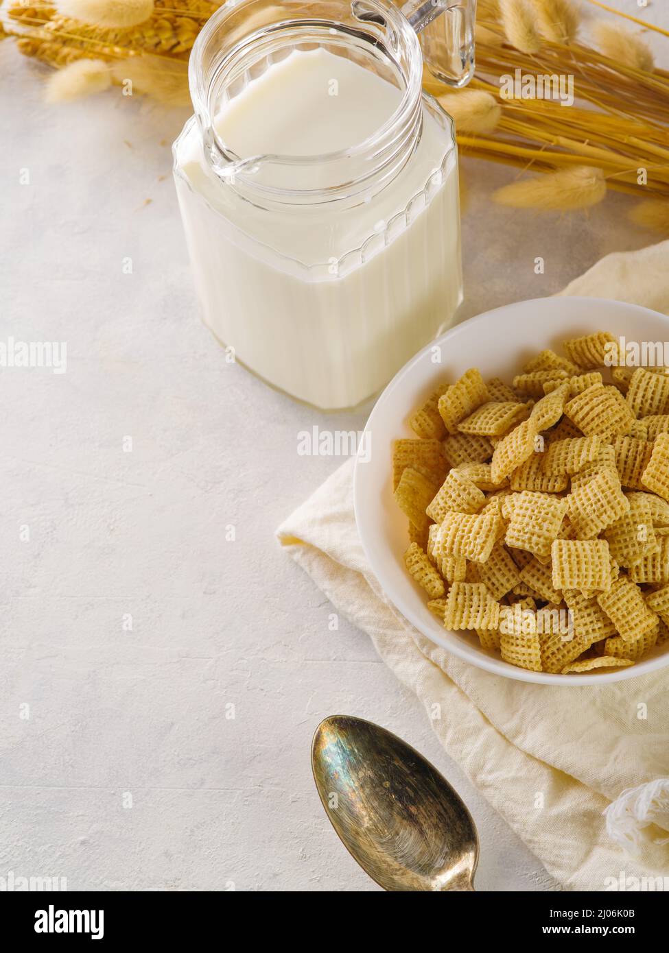 Crispy whole grain pads in a bowl and milk in a jug. Isolated on white ...