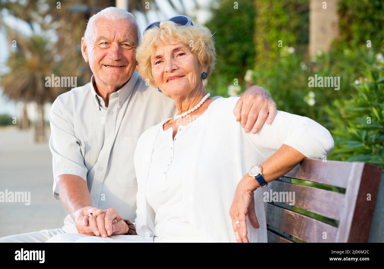 positive mature couple of male and female sitting on bench Stock Photo ...