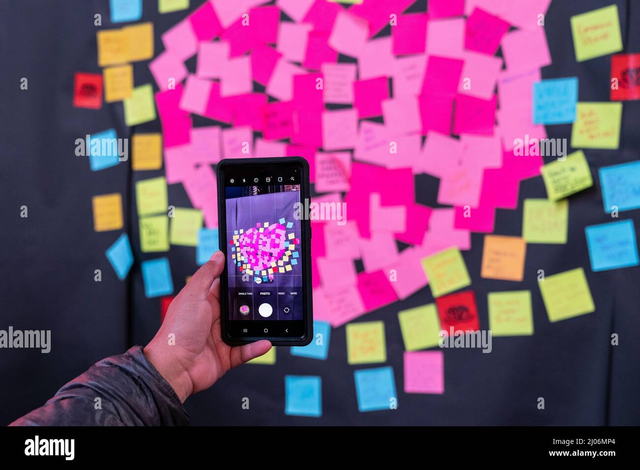 New York, NY - March 16, 2022: A woman takes a photo of messages ...