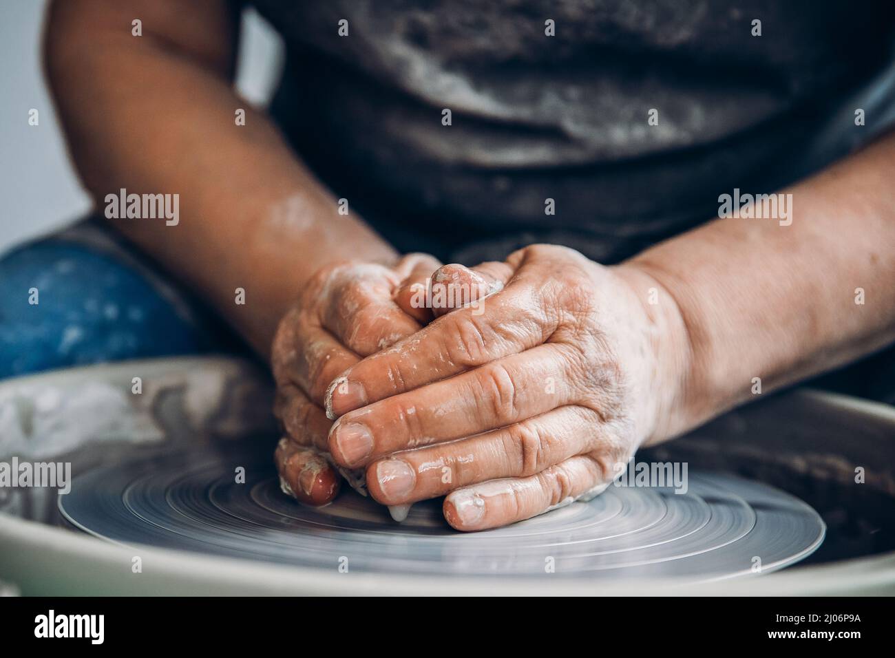 Wrinkled hands wizard on potter wheel makes clay dishes. Place to work ...