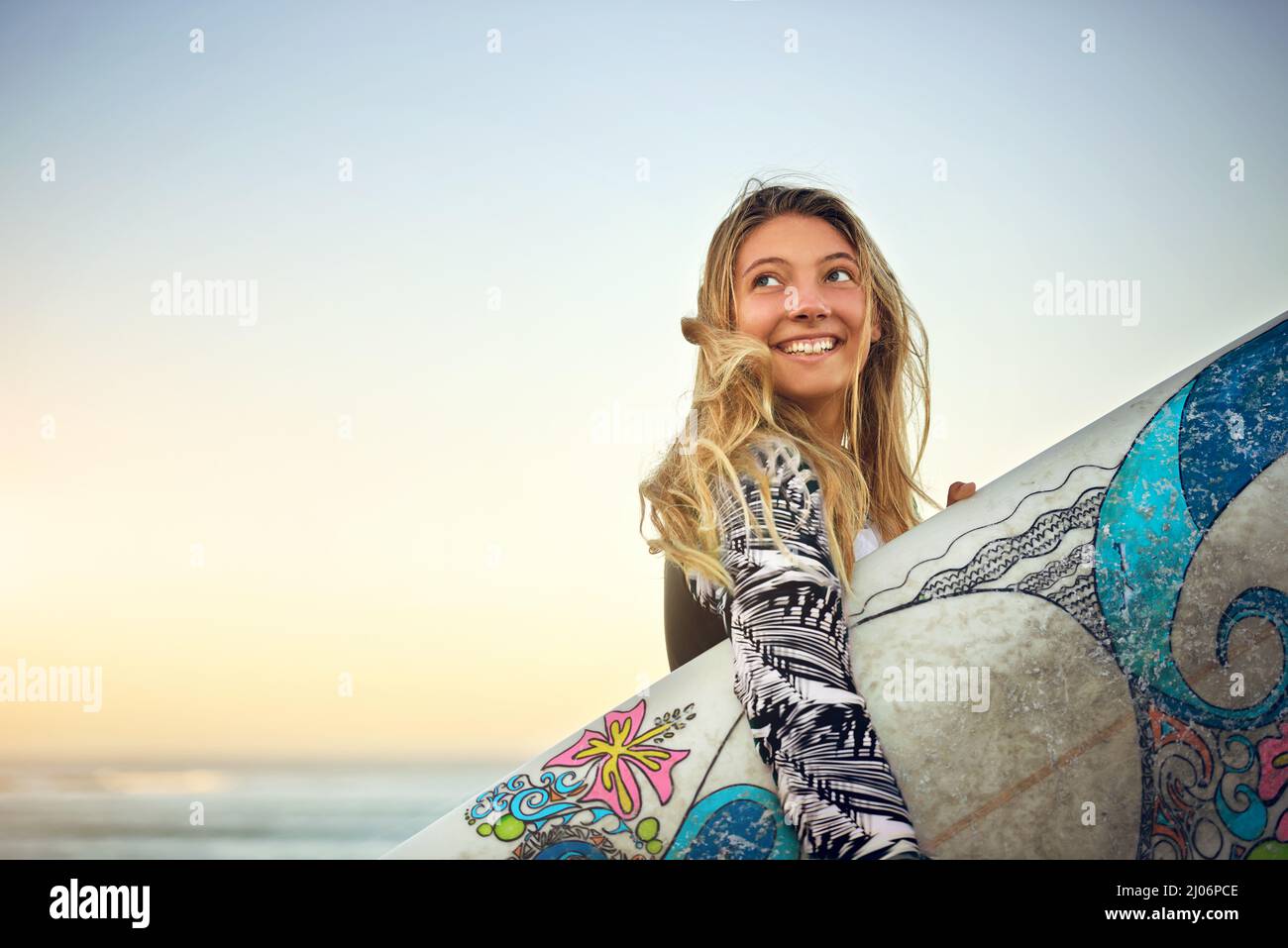 Shes got surfing on her mind. Cropped shot of an attractive young female surfer standing with ...